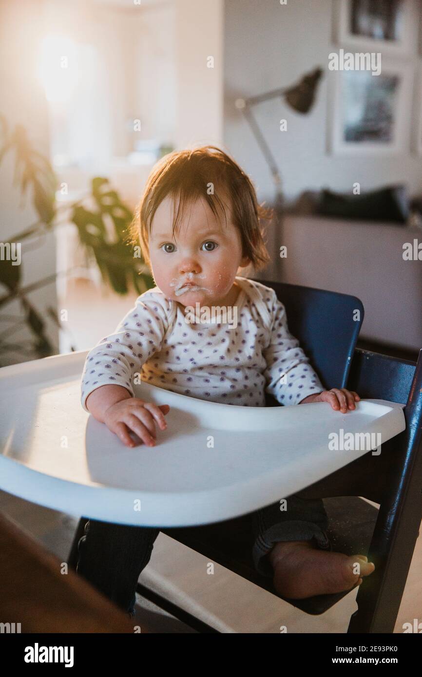 Toddler girl sitting in high chair Stock Photo - Alamy