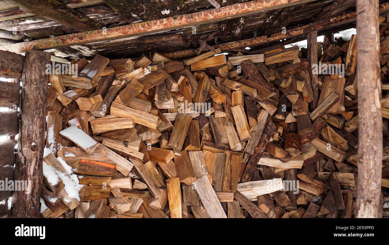 Logging in the village. Chopped logs under a canopy in winter. Natural ...