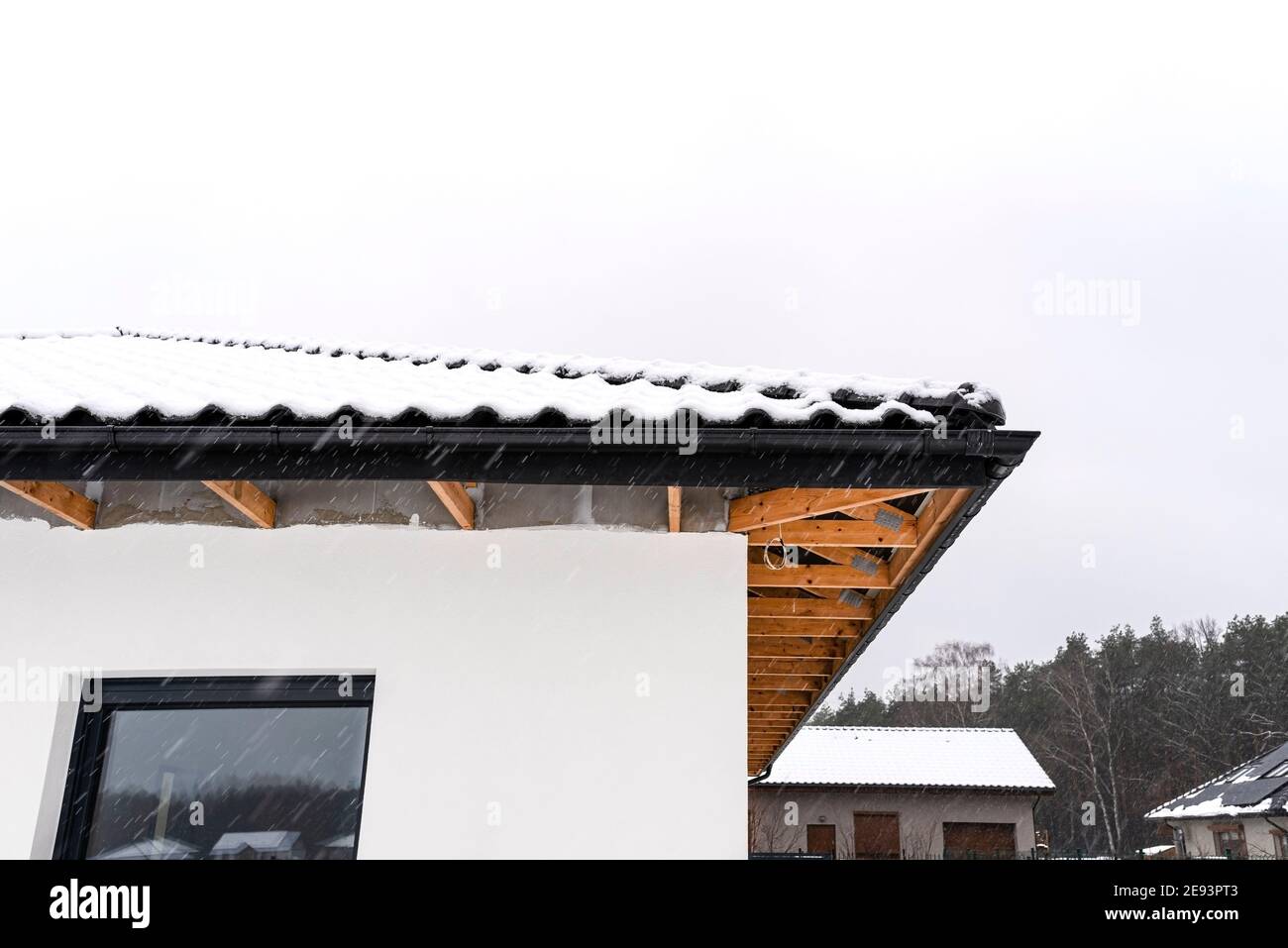 The roof of a single-family house is covered with snow against a cloudy ...