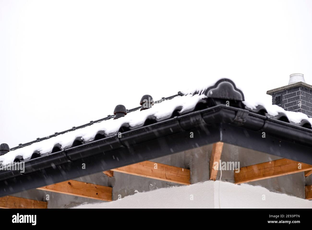 The roof of a single-family house is covered with snow against a cloudy ...