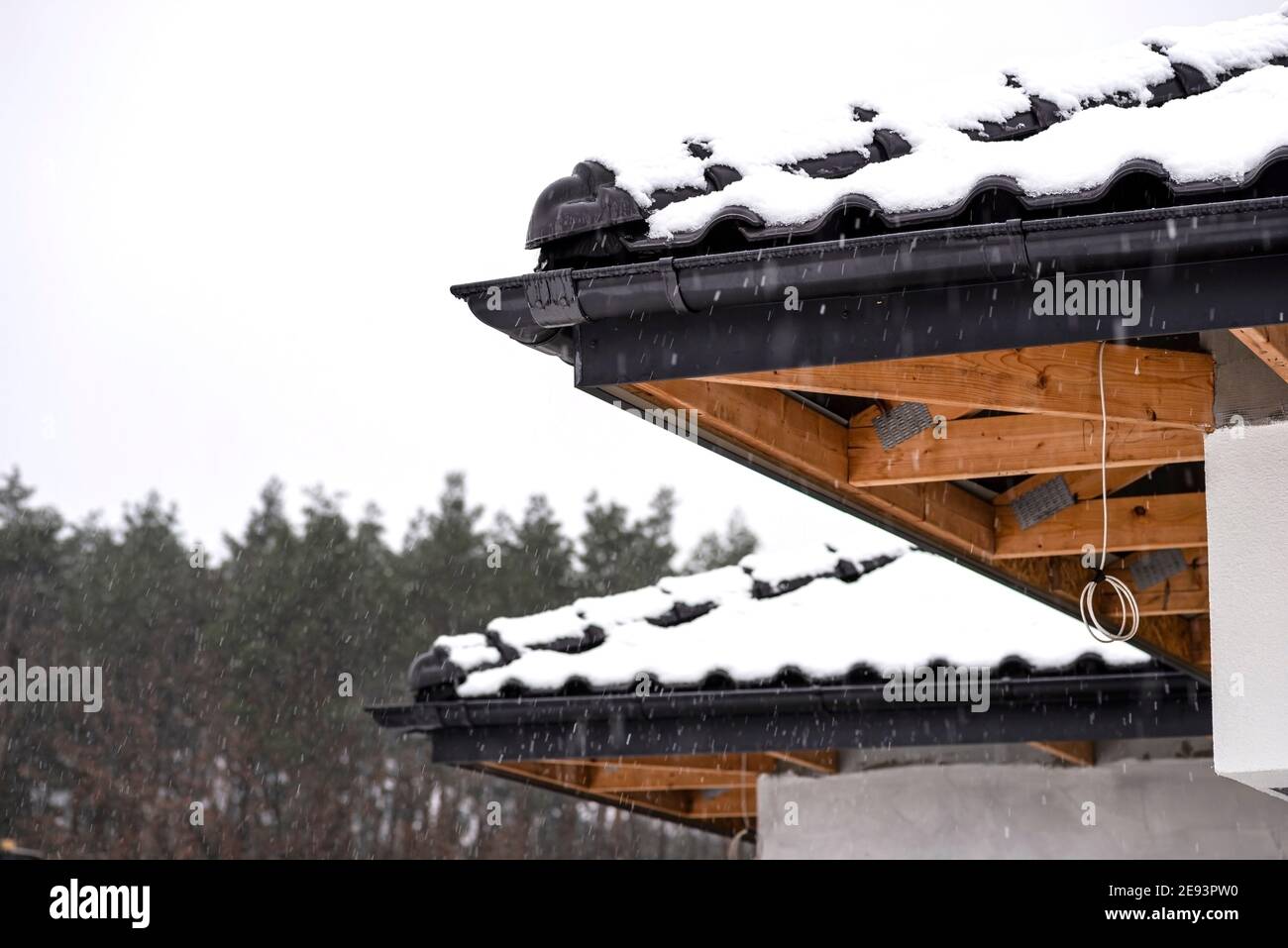 The corner of the roof of a single-family house is covered with snow ...