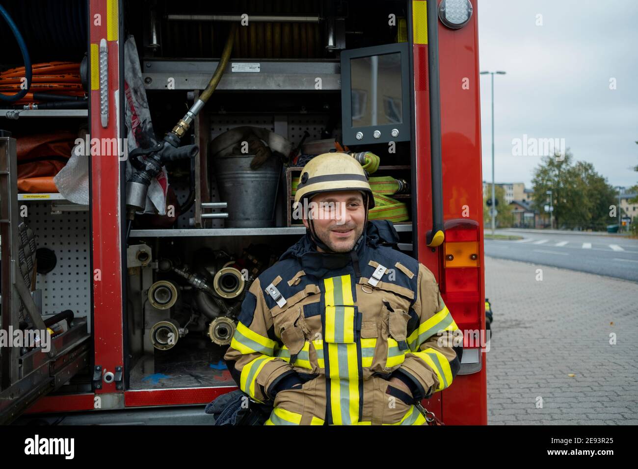 Smiling firefighter in front of fire engine Stock Photo - Alamy