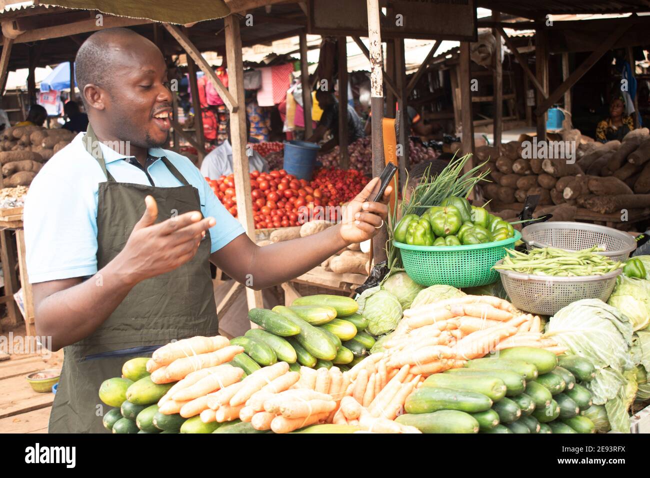 an african market seller holding his phone while smiling Stock Photo ...