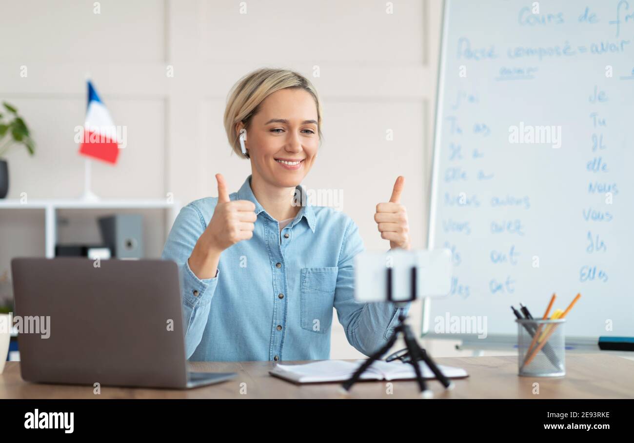 Positive foreign languages teacher giving online French lesson using ...