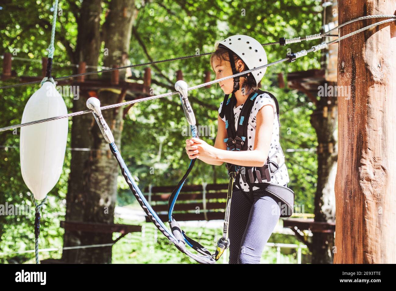 Little girl with safety equipment at the forest adventure park ...