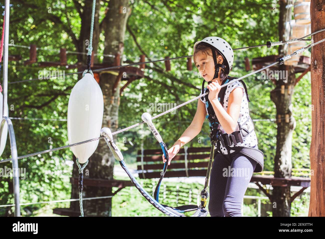 Little girl with safety equipment at the forest adventure park ...