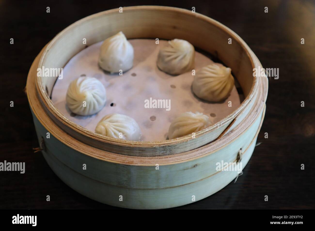 Set of six handmade dessert dumplings in a round bamboo steam basket ...