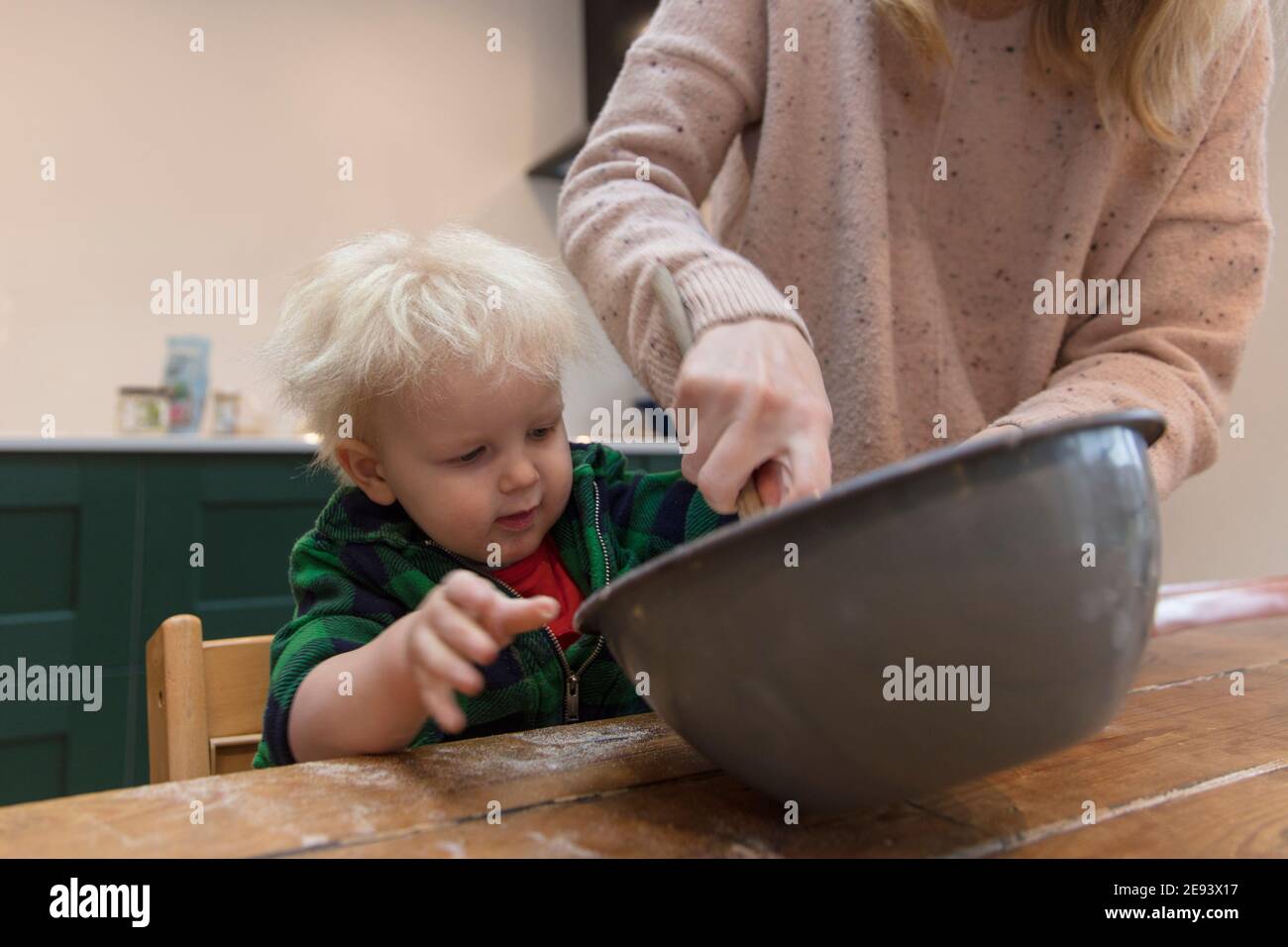 Mother and child mixing ingredients in a bowl in the kitchen together ...