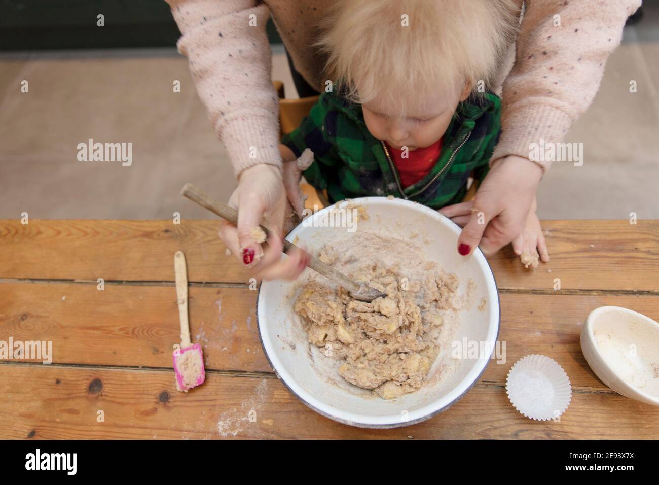 Mother and child mixing ingredients in a bowl in the kitchen together ...