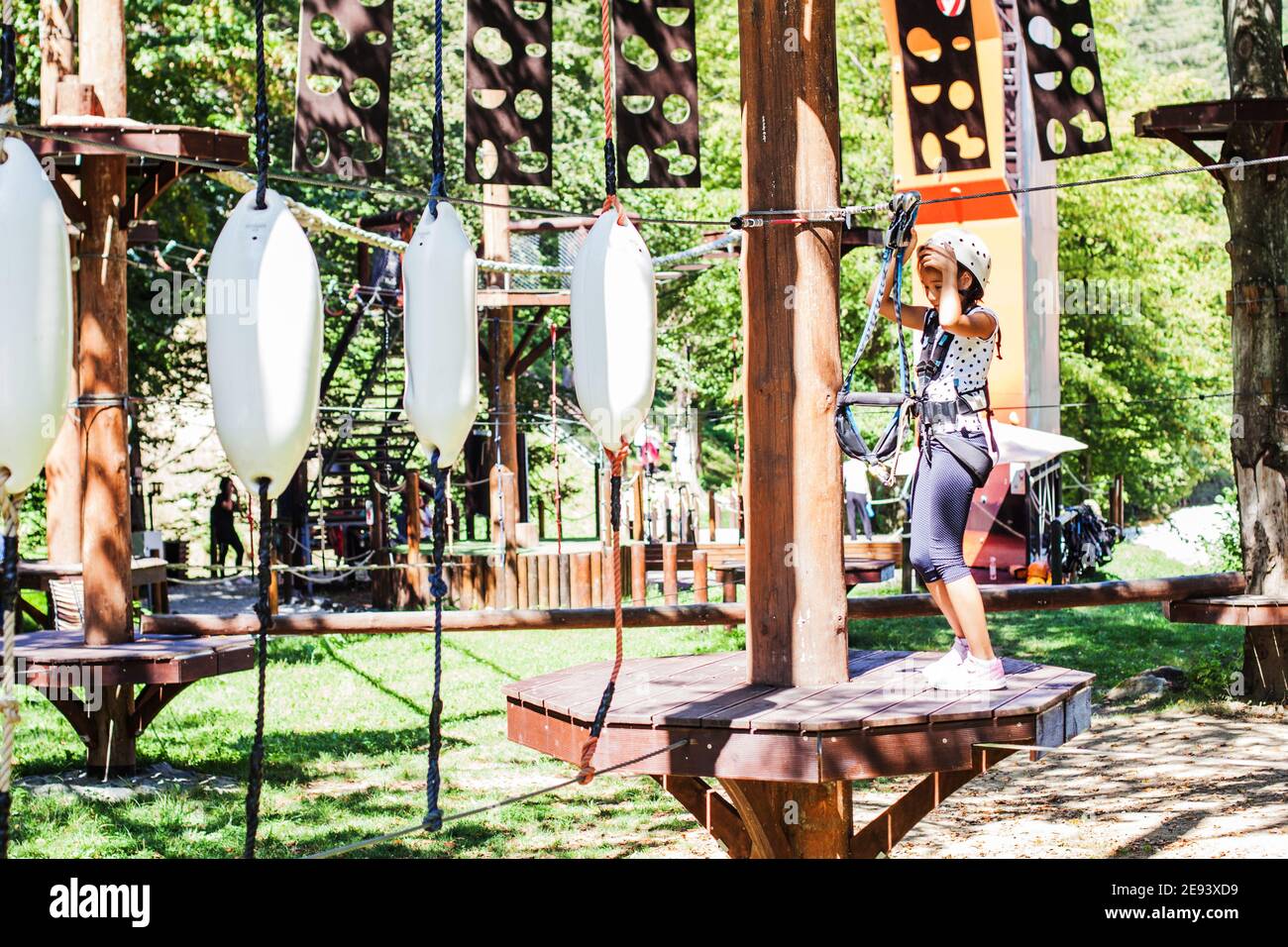 Little girl with safety equipment at the forest adventure park ...
