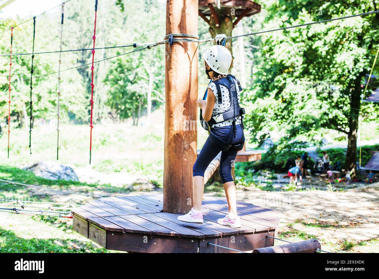 Little girl with safety equipment at the forest adventure park ...