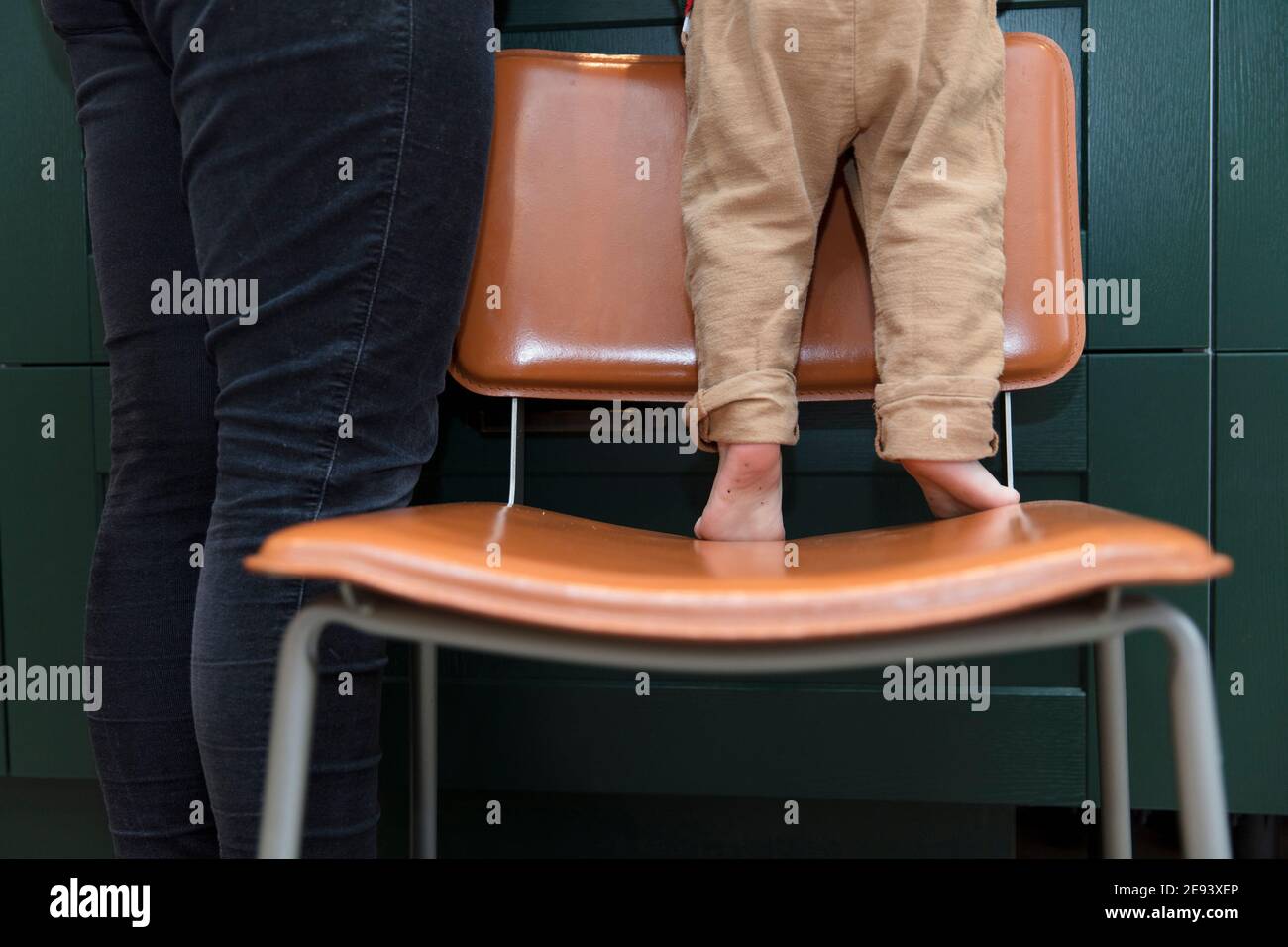 Young boy stood on a chair helping mum to bake a cake in the kitchen ...