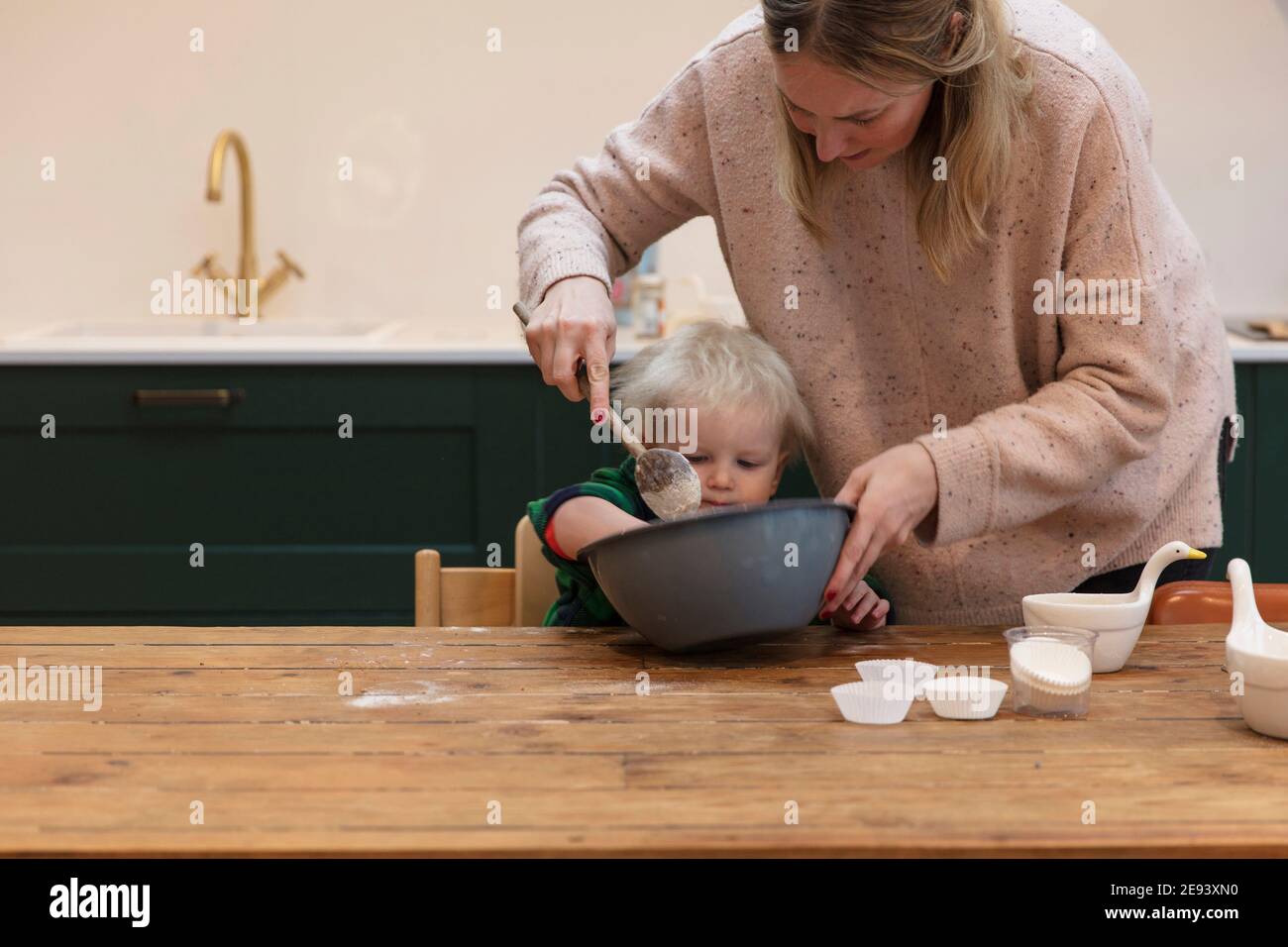 Mother and child mixing ingredients in a bowl in the kitchen together ...