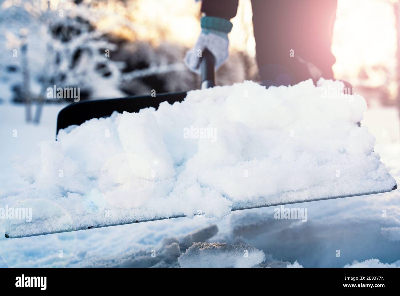 Close up of a person clearing snow from the sidewalk with a snow shovel ...