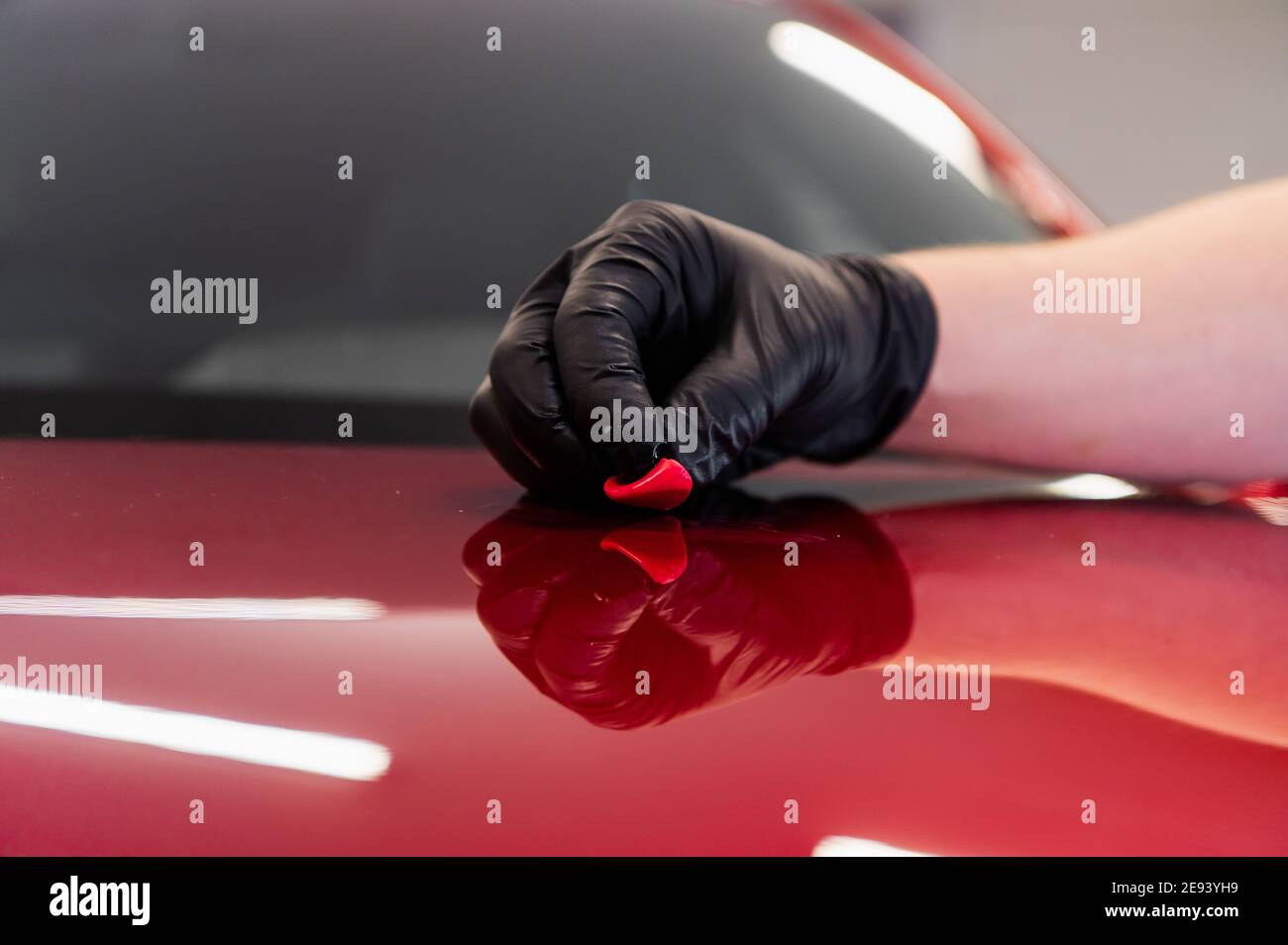 The master removes small dirt pieces from the car bonnet surface with ...