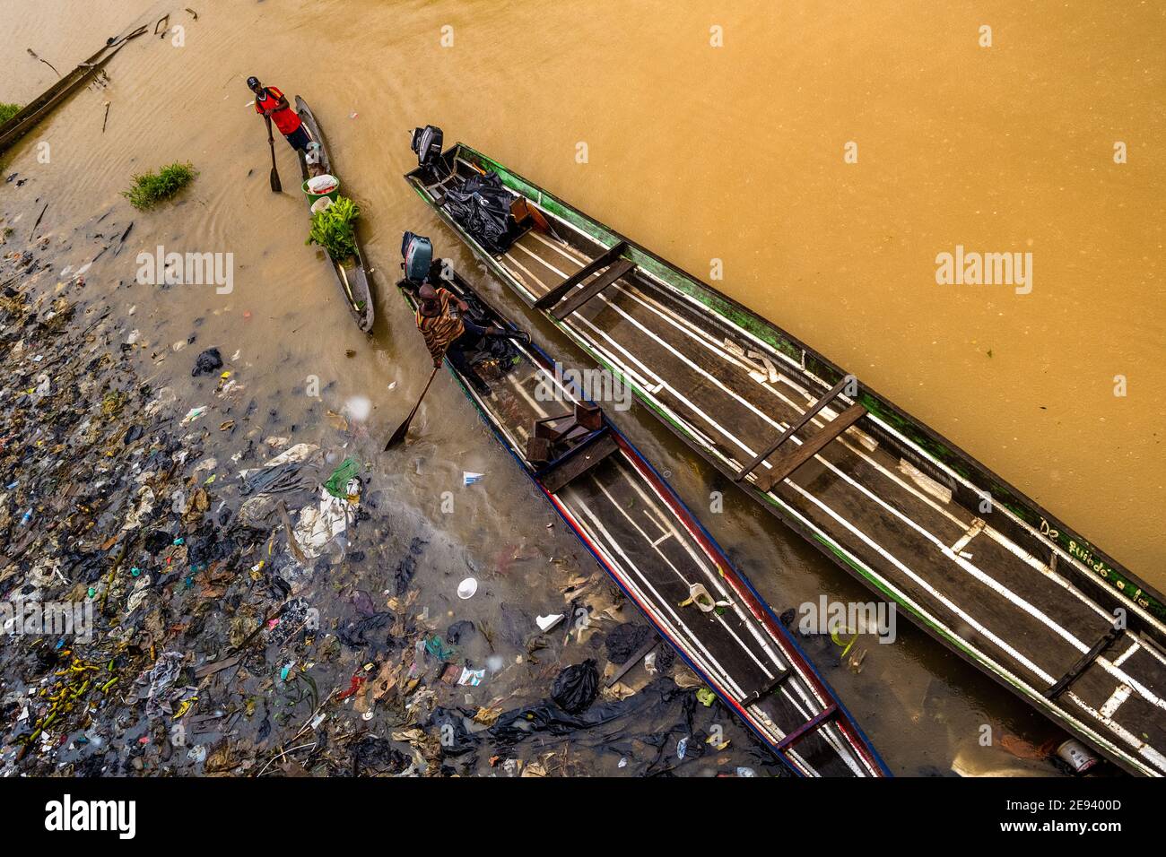 Afro-Colombian men navigate wooden boats along the shore in the Atrato ...