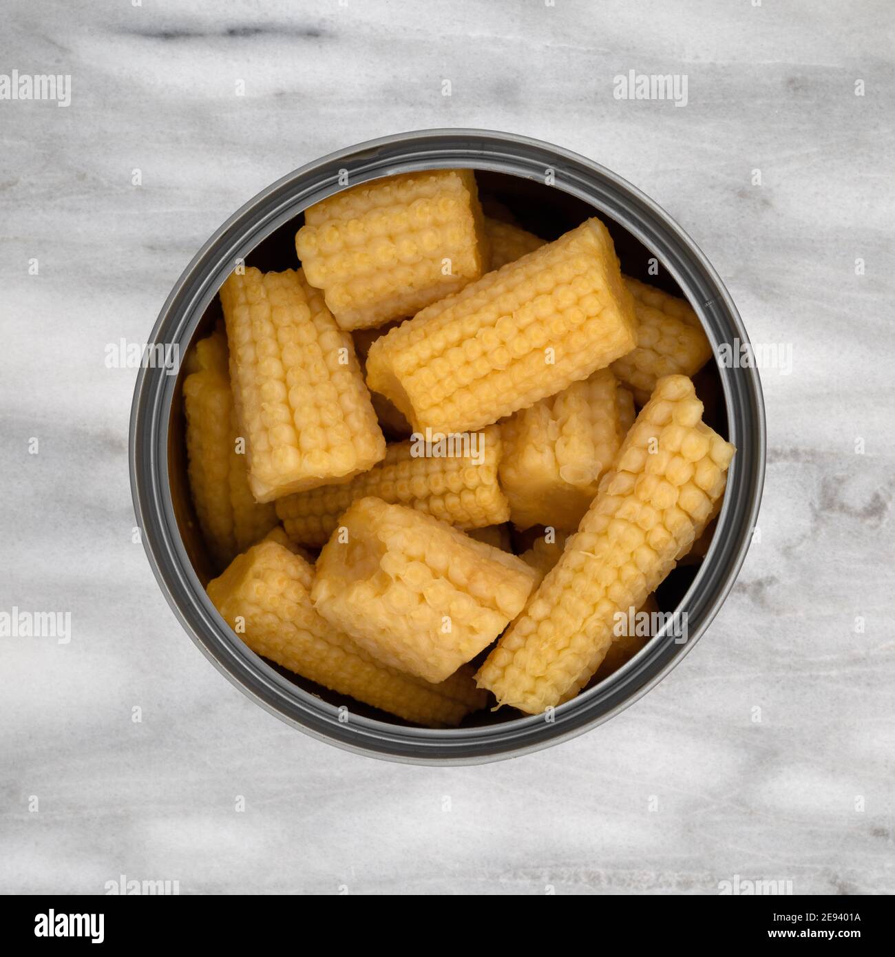 Overhead view of an open can filled with organic baby corn on a gray ...