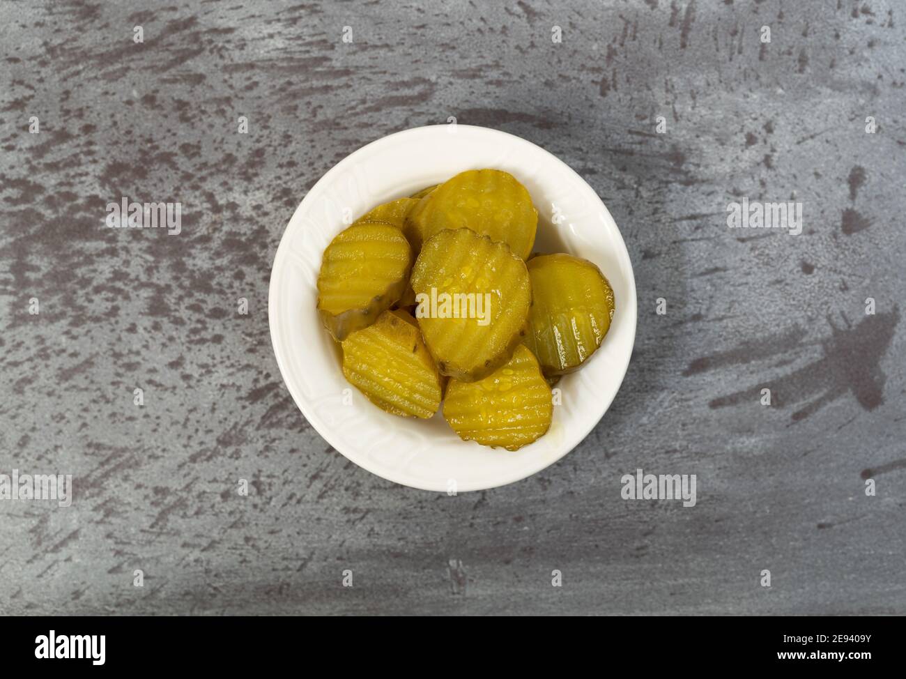 Top view of a small white bowl filled with hamburger dill pickle slices ...