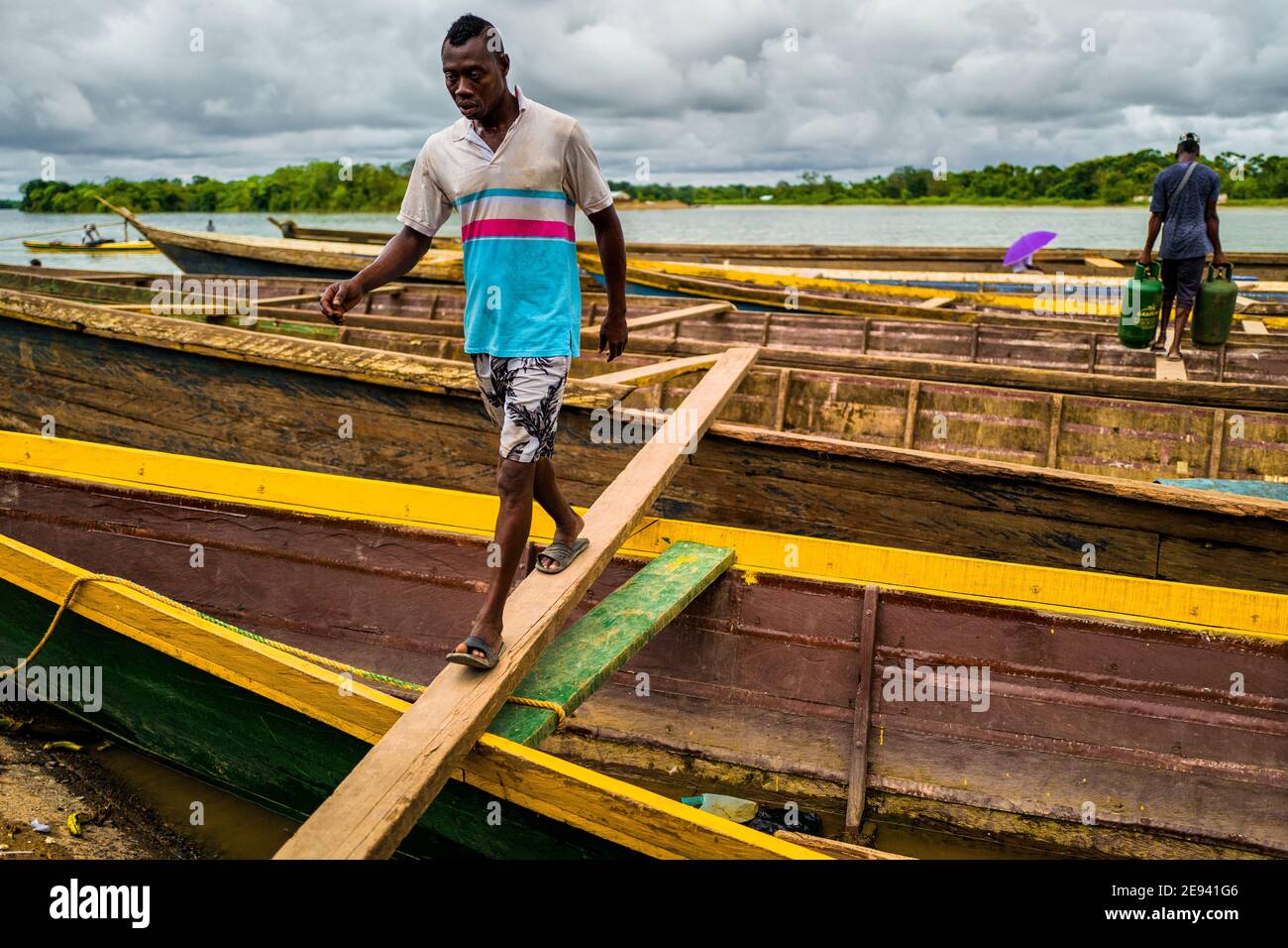 An Afro-Colombian worker walks on the top of wooden cargo boats ...