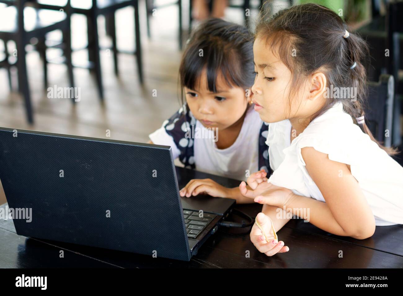 Laos, Don Dhet. Horizontal view of two girls taking a lesson through a ...