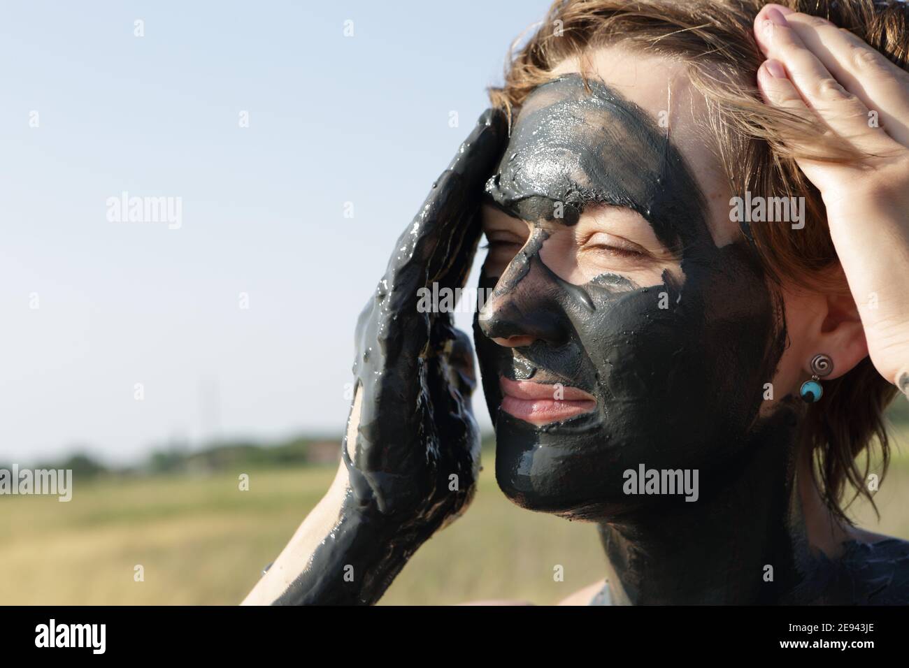 Woman applying black healing mud on her face Stock Photo - Alamy
