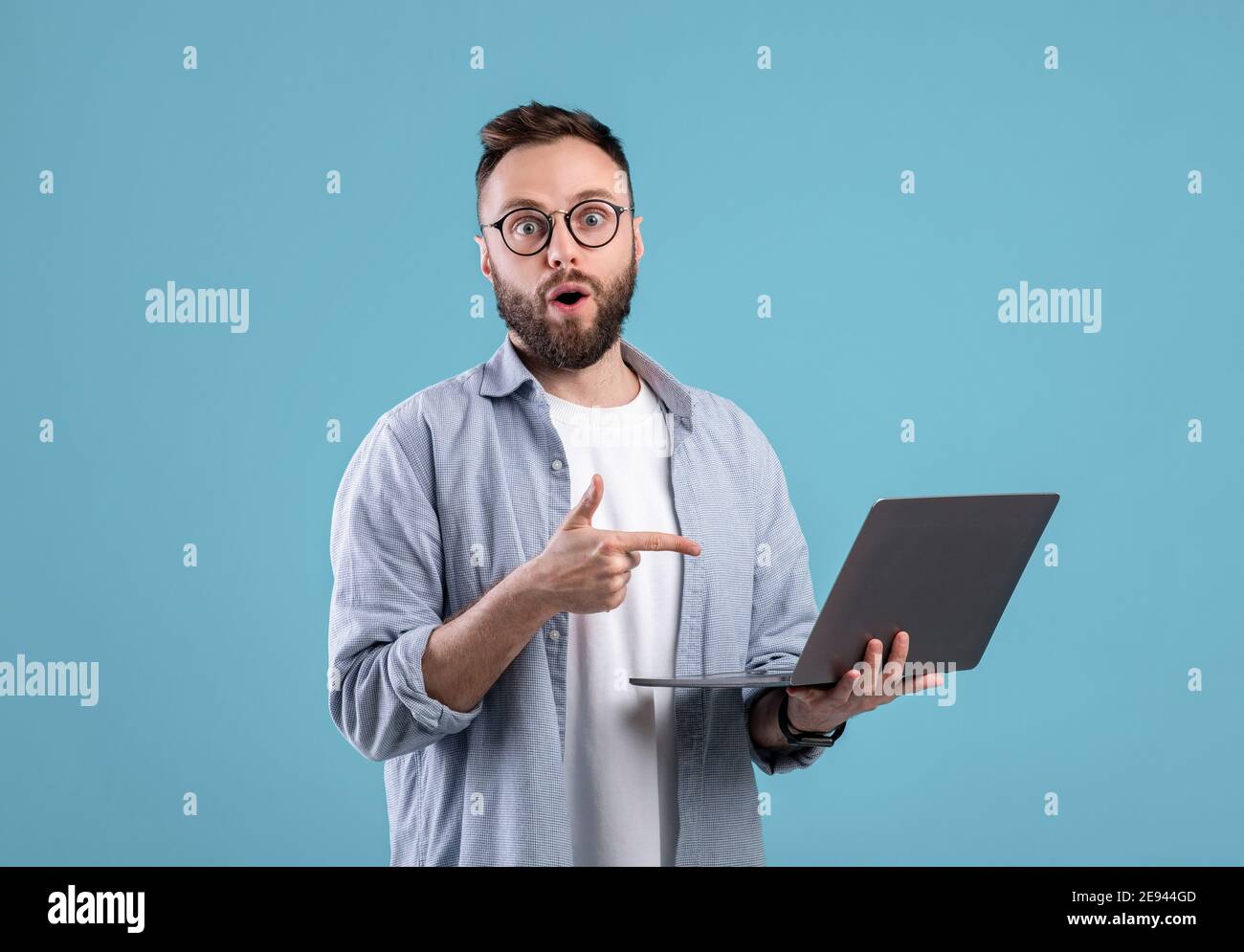 Surprised millennial guy opening mouth in awe, pointing at laptop ...