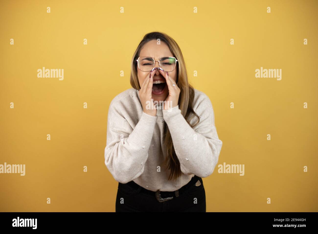 Pretty woman with long hair shouting and screaming loud with hands on ...