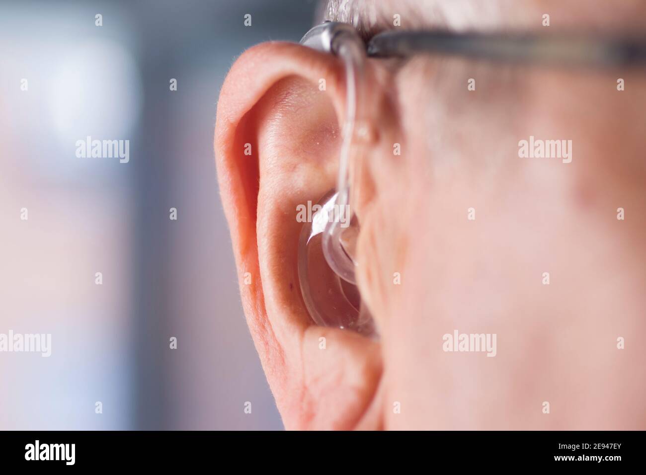 Caucasian white old aged man wearing modern digital hearing aid in ear ...
