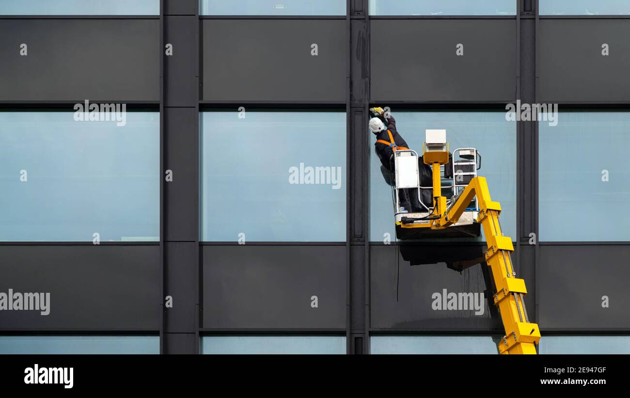 Male window cleaner cleaning glass windows on modern building high in ...