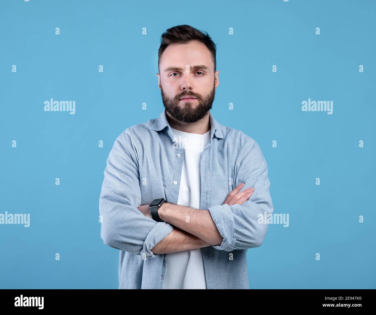 Portrait of serious millennial guy posing with crossed arms and looking ...