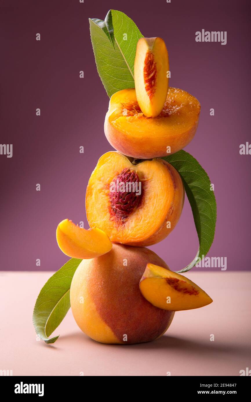 Flying fresh ripe peach in slices and whole fruits with green leaves ...