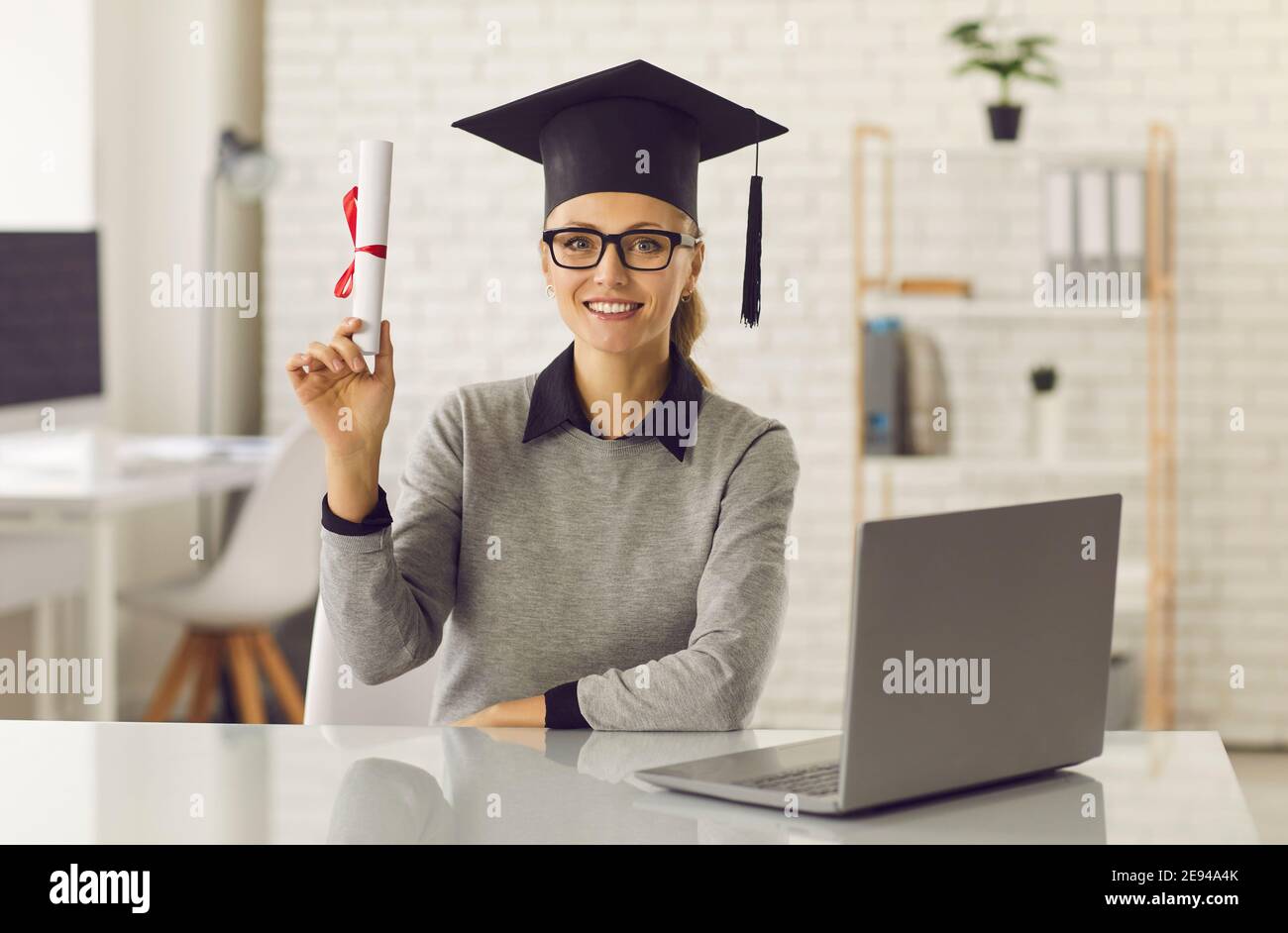 Talented online courses graduate sitting at desk with laptop and ...