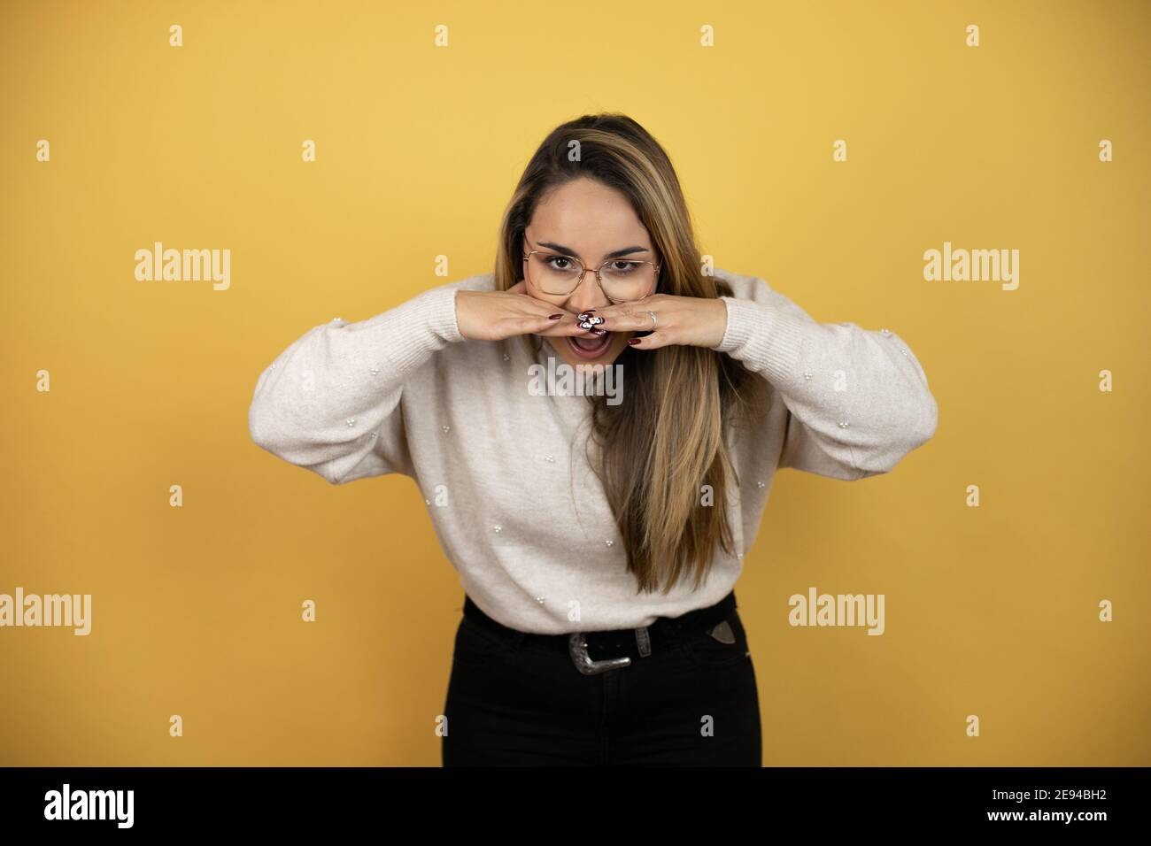 Pretty woman with long hair shouting and screaming loud down with hands ...