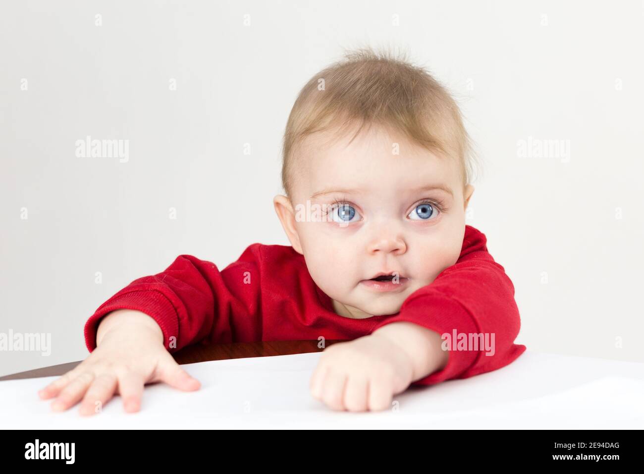 A small child is standing at the table waiting to be fed Stock Photo ...