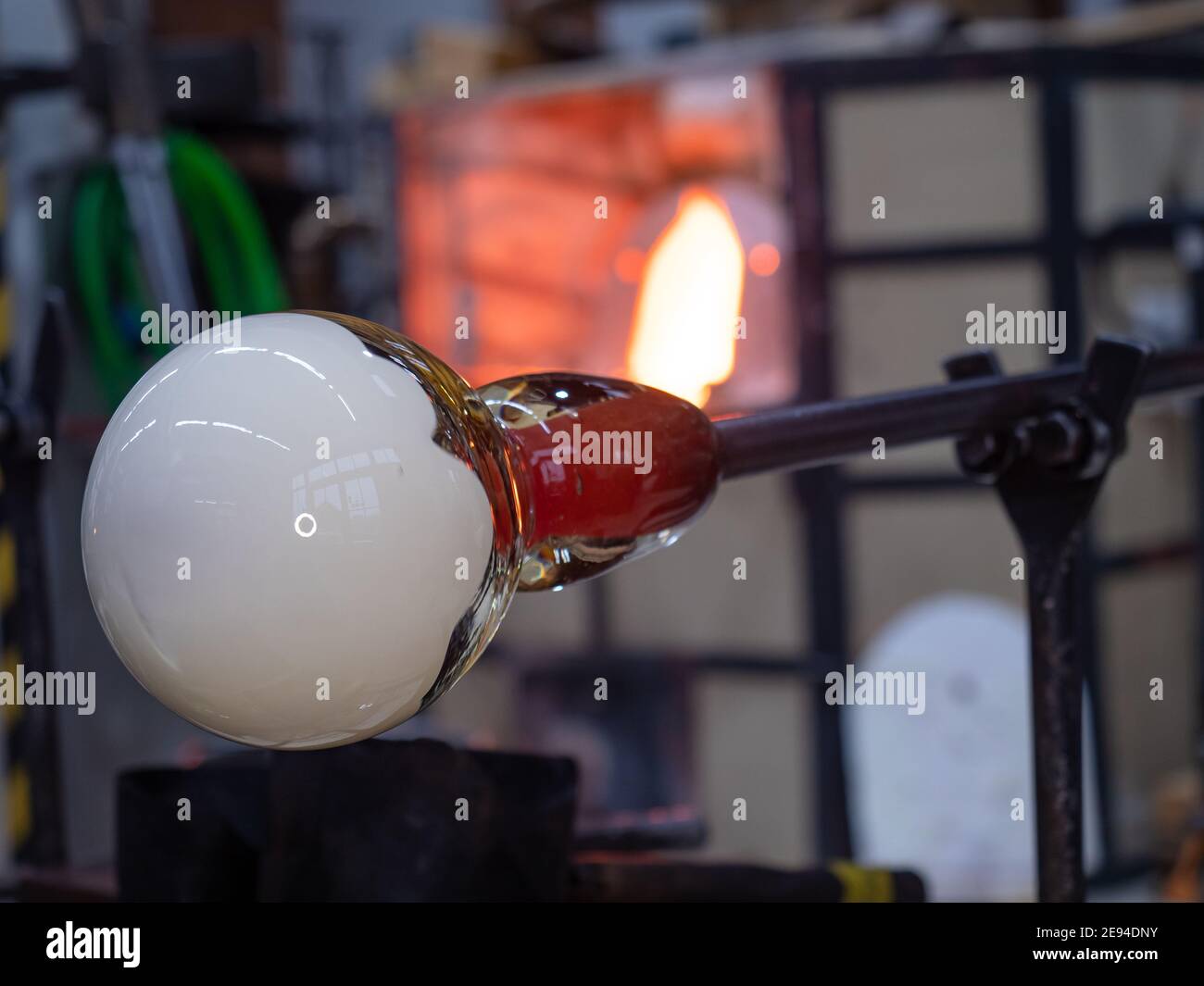 Artistic glassblower forms a work of art at the end of a glass pipe. In ...