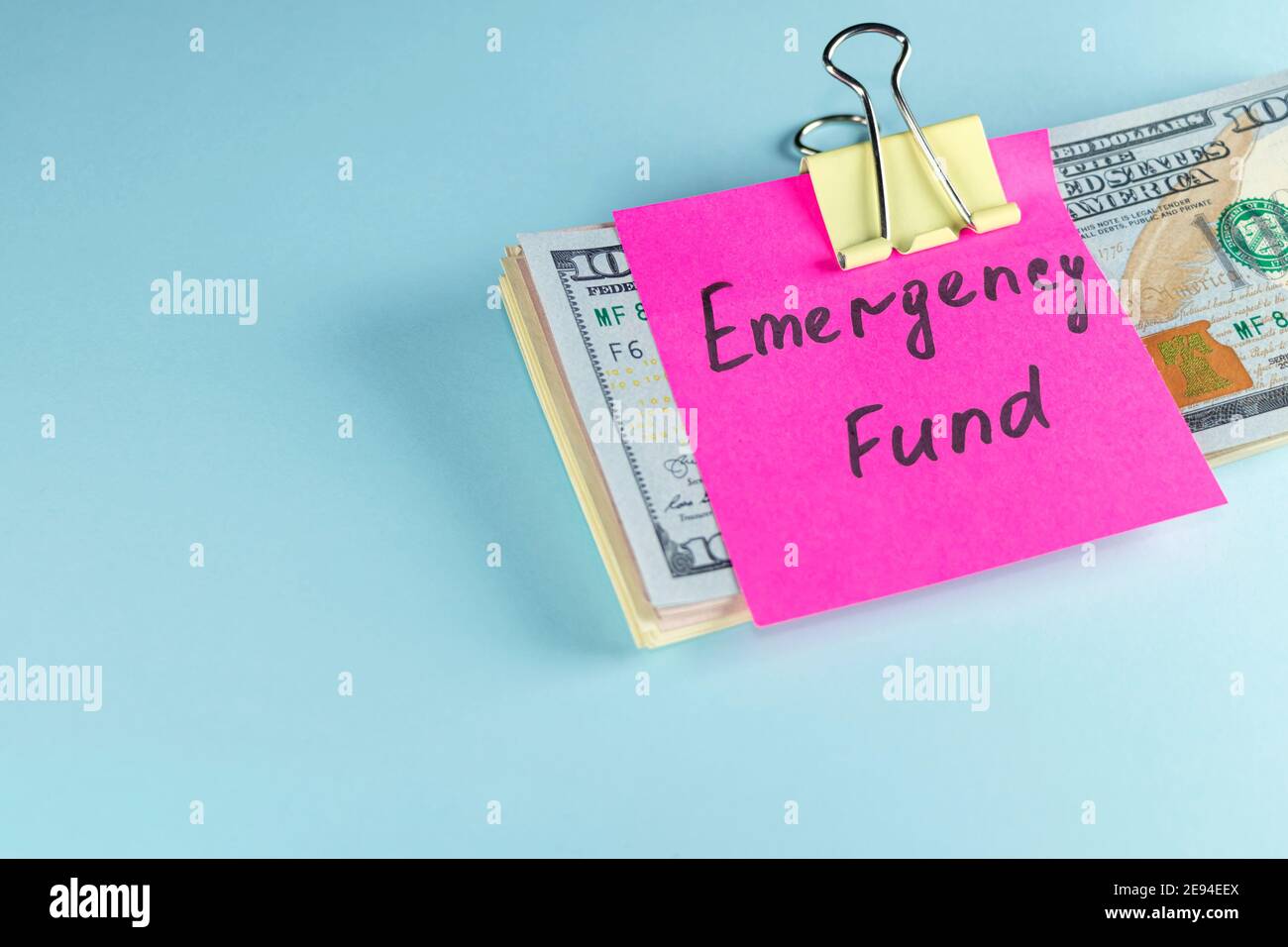 US dollars in paper clip on pastel blue background with note written ...