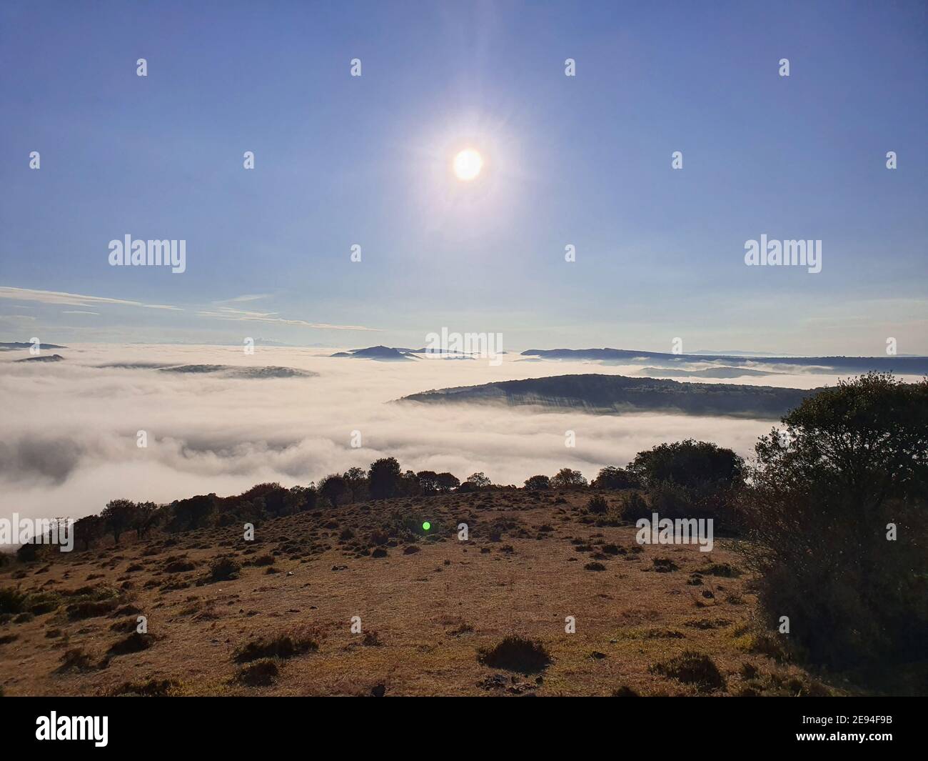 Beautiful shining sun over clouds covering mountains Stock Photo - Alamy