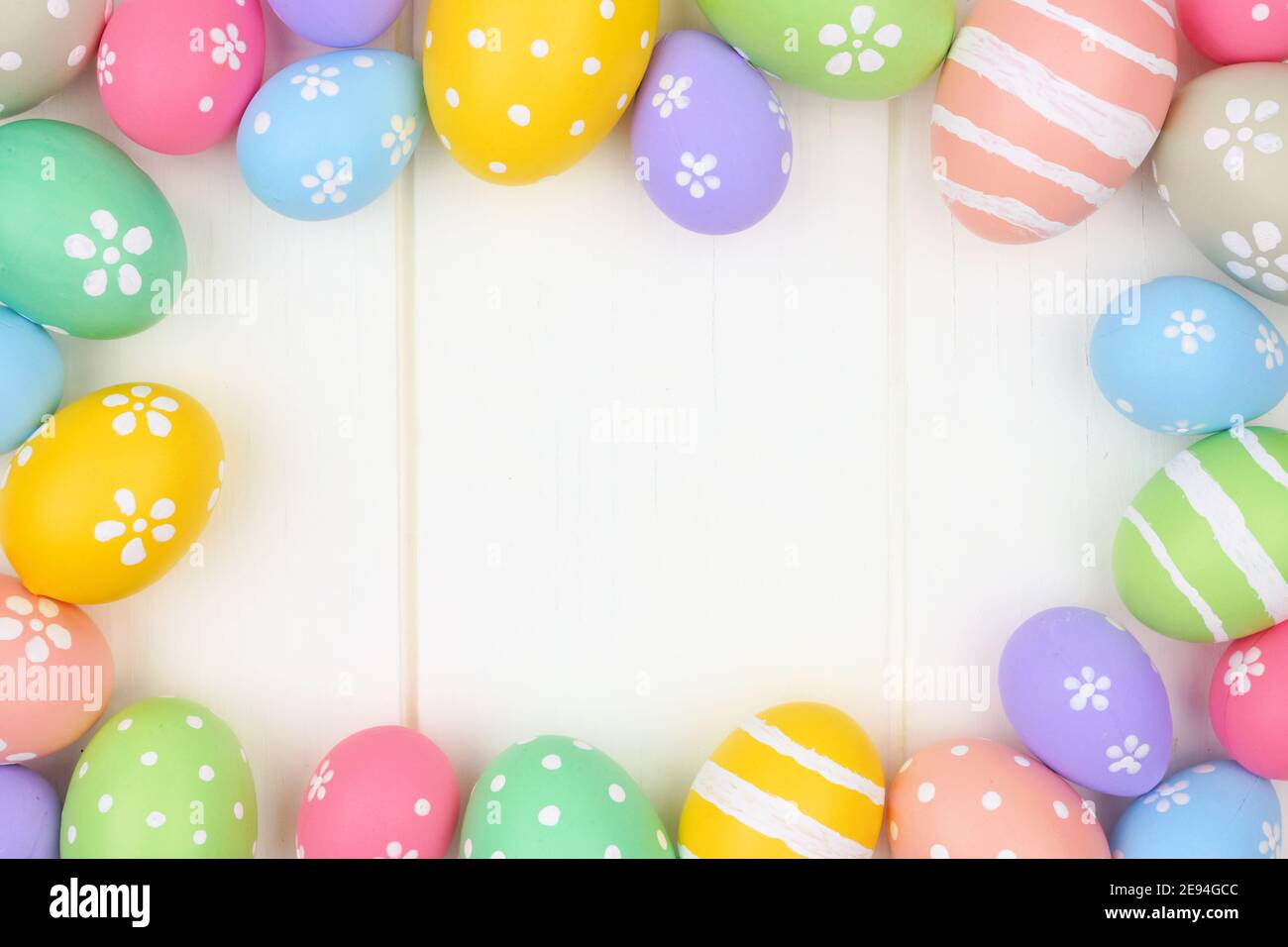 Colorful pastel Easter Egg frame against a white wood background. Top ...