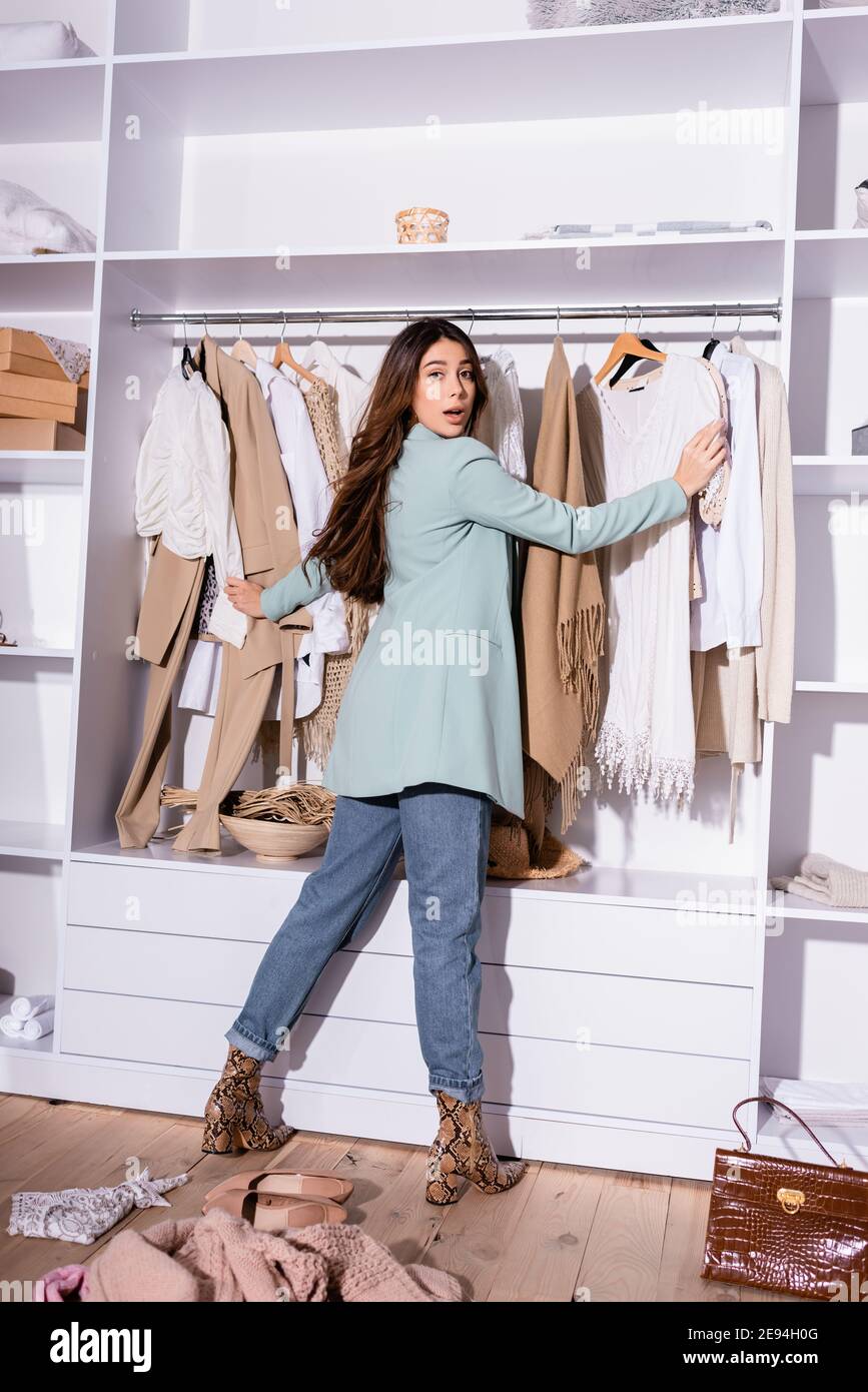 Back view of woman looking at camera while standing near clothes in ...