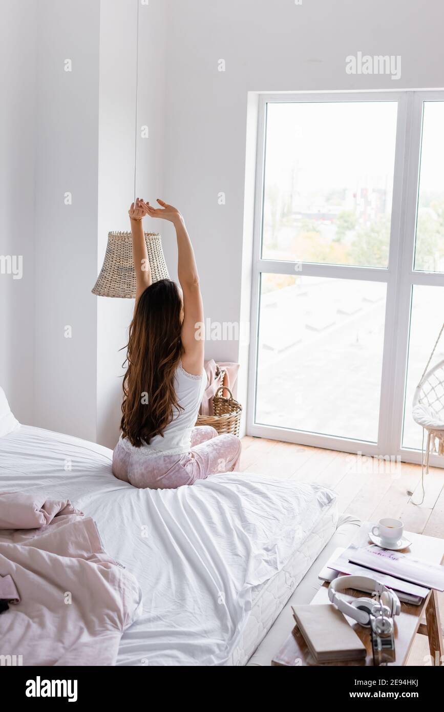 Back view of brunette woman stretching on bed during morning Stock ...