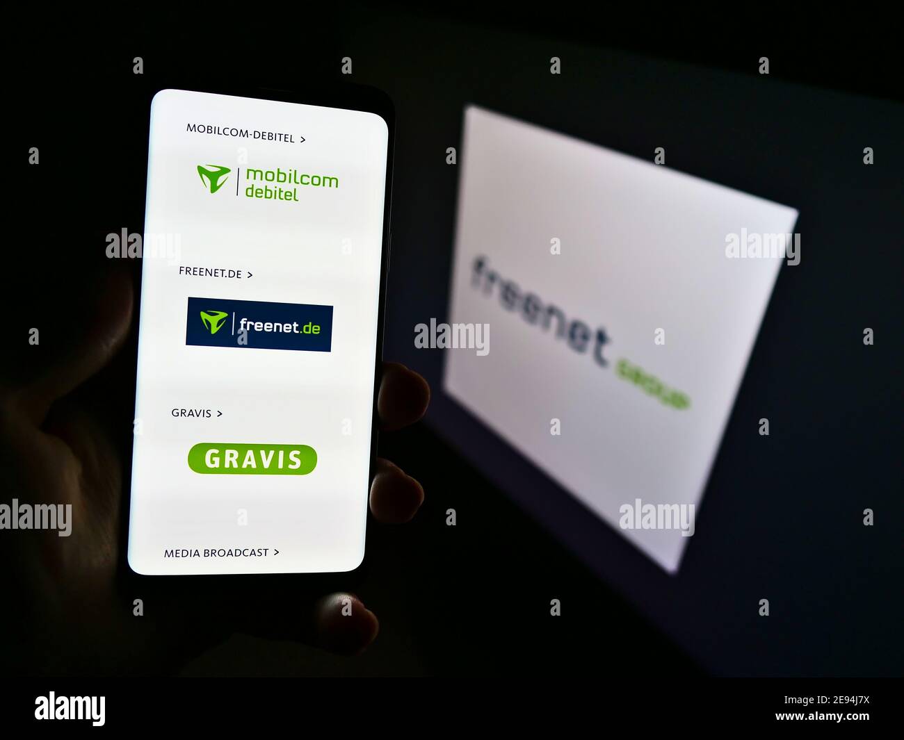 Person holding smartphone with brands of German telecommunications provider Freenet AG on ...