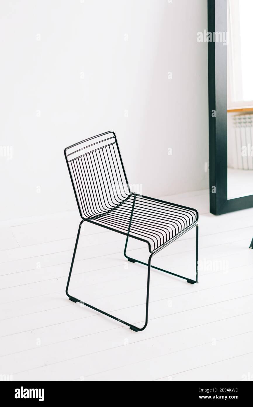 Black metal modern chair in white room near big mirror Stock Photo - Alamy