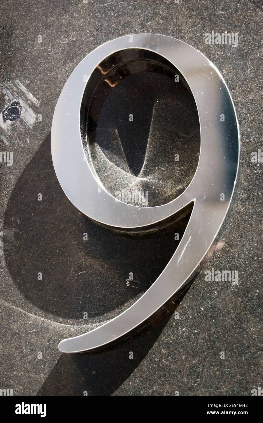 Metal figure nine, 9, on the marble outside wall of an office block in ...