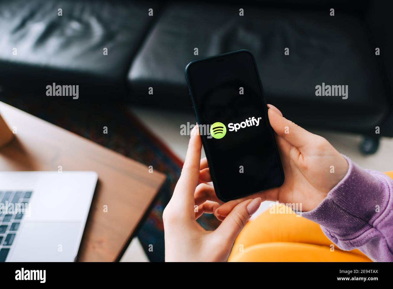 Hand holding iPhone with Spotify app logo on the screen Stock Photo - Alamy