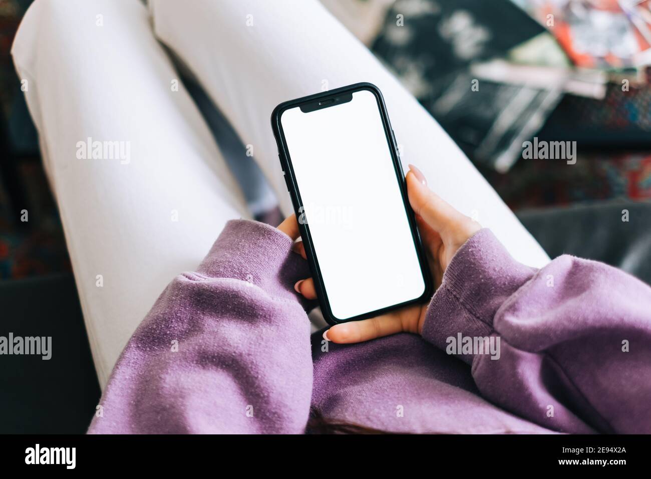 Woman holding a smartphone with a white screen mock up, resting on the ...
