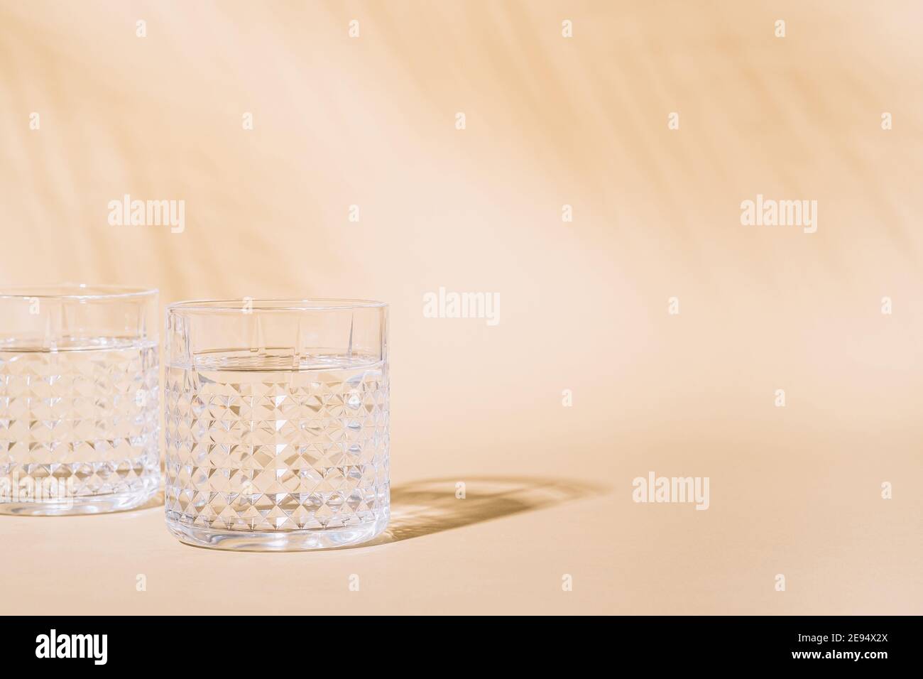 Glass of water on pastel background with hard shadow Stock Photo - Alamy