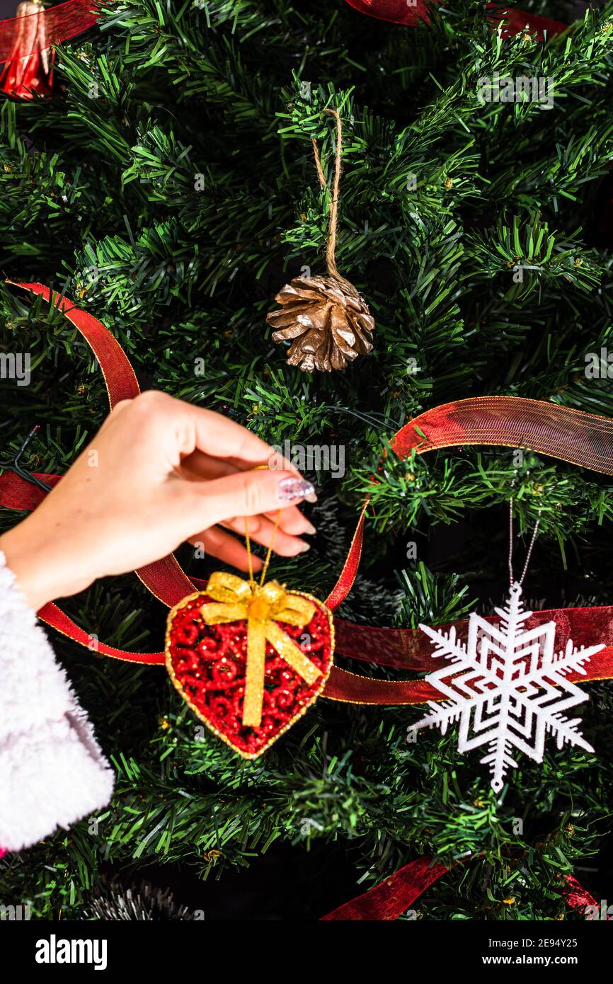 Decorating Christmas tree, hand putting Christmas decorations on fir ...