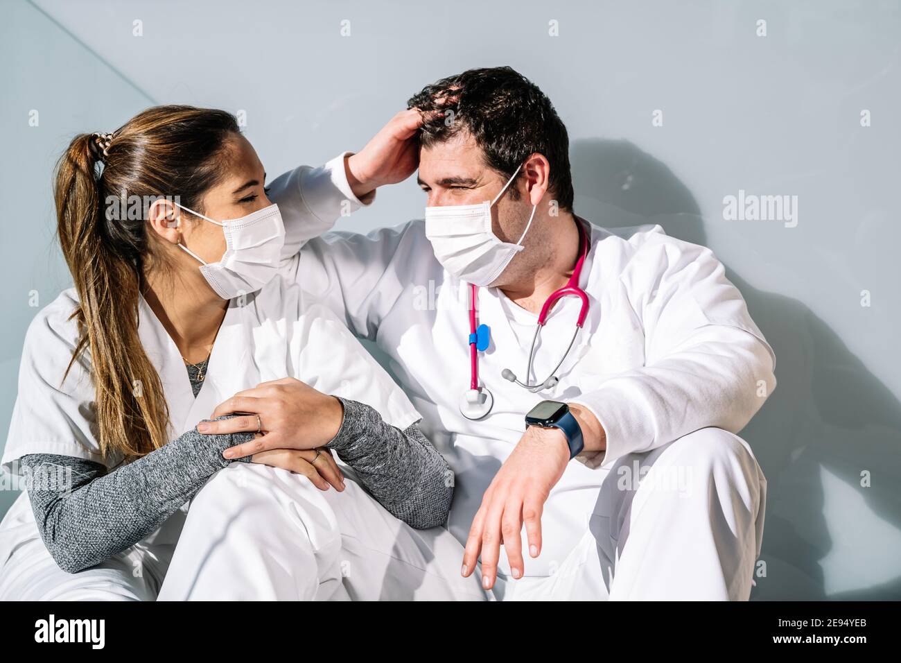 two nurses look at each other and comfort each other as they rest on ...