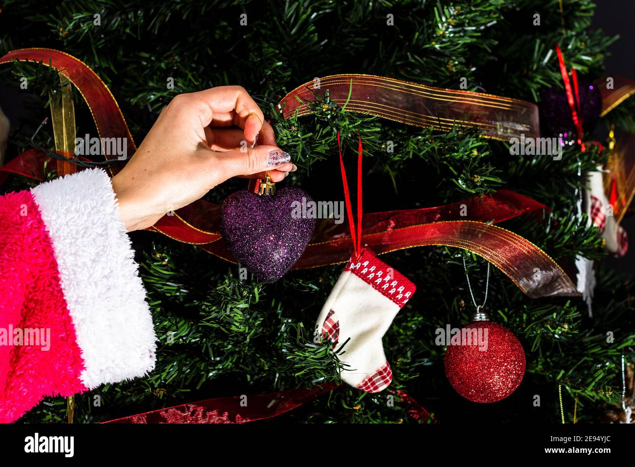 Decorating Christmas tree, hand putting Christmas decorations on fir ...