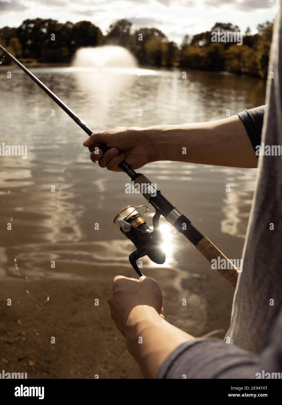 Vertical shot of a male fishing in the lake under the sunligh Stock ...